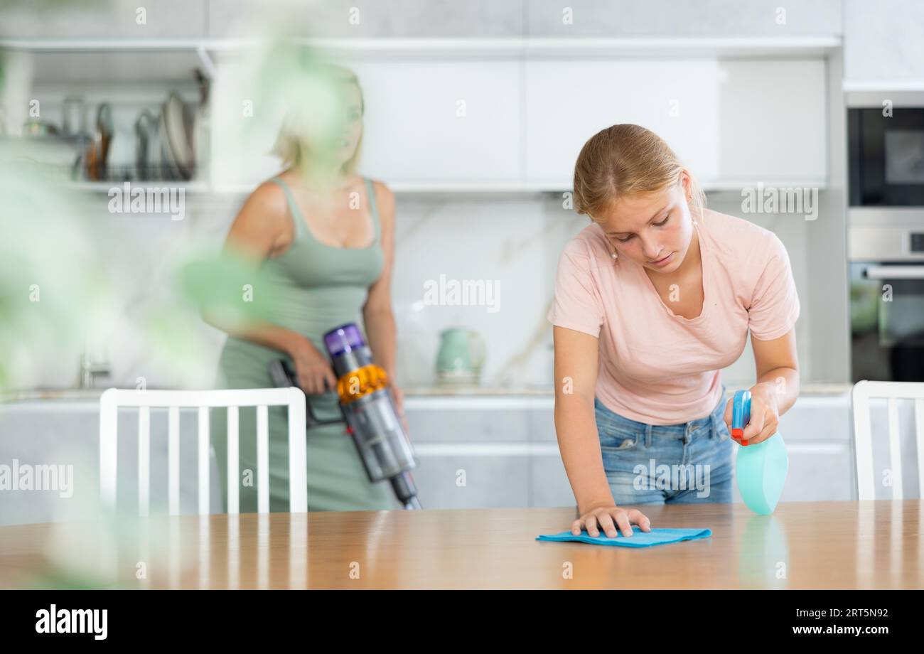 Teenage girl wiping table with rag and detergent at home kitchen Stock ...