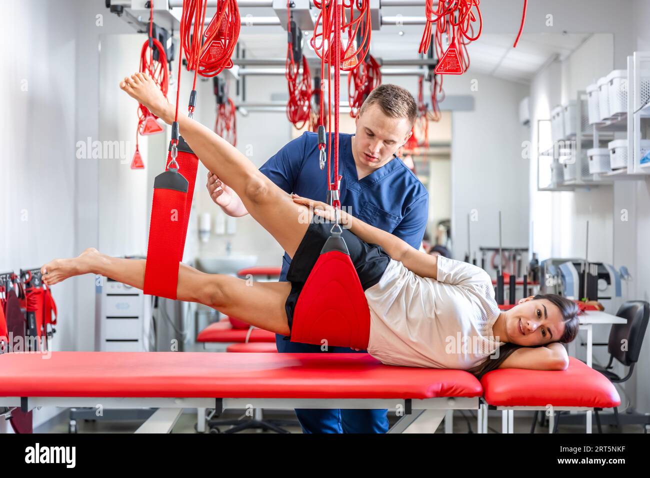 Female patient hanging on suspensions at rehabilitation center Stock ...