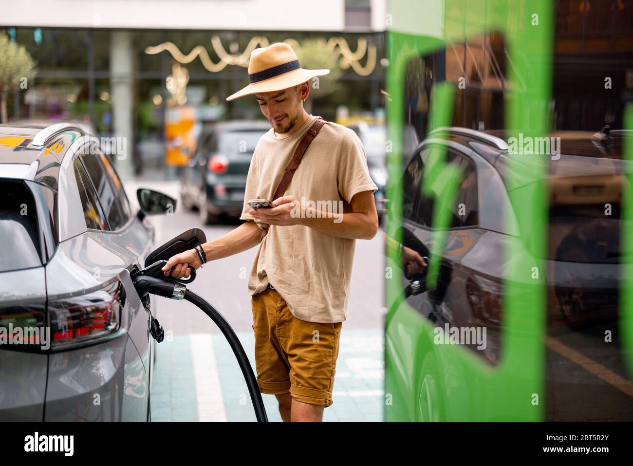 Man charging electric car on a public charging station Stock Photo - Alamy
