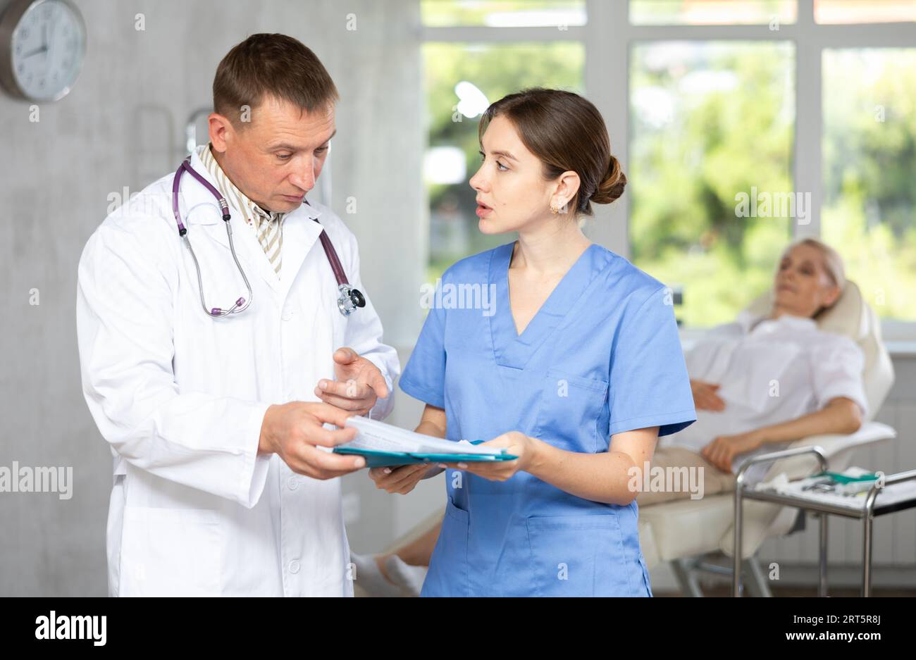 Two doctors with papers in hands discussing clinical diagnosis of ...