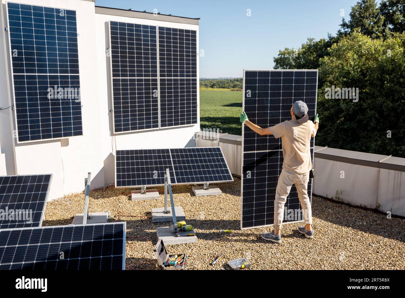 Man installing solar panels on a rooftop Stock Photo - Alamy