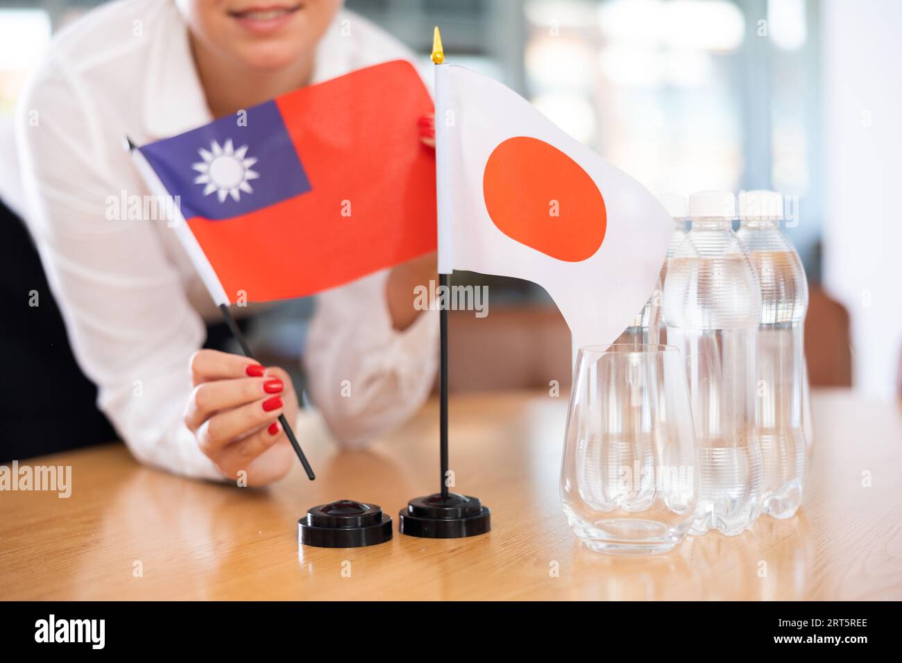 Female hands placing flags of Taiwan and Japan on table before meeting ...