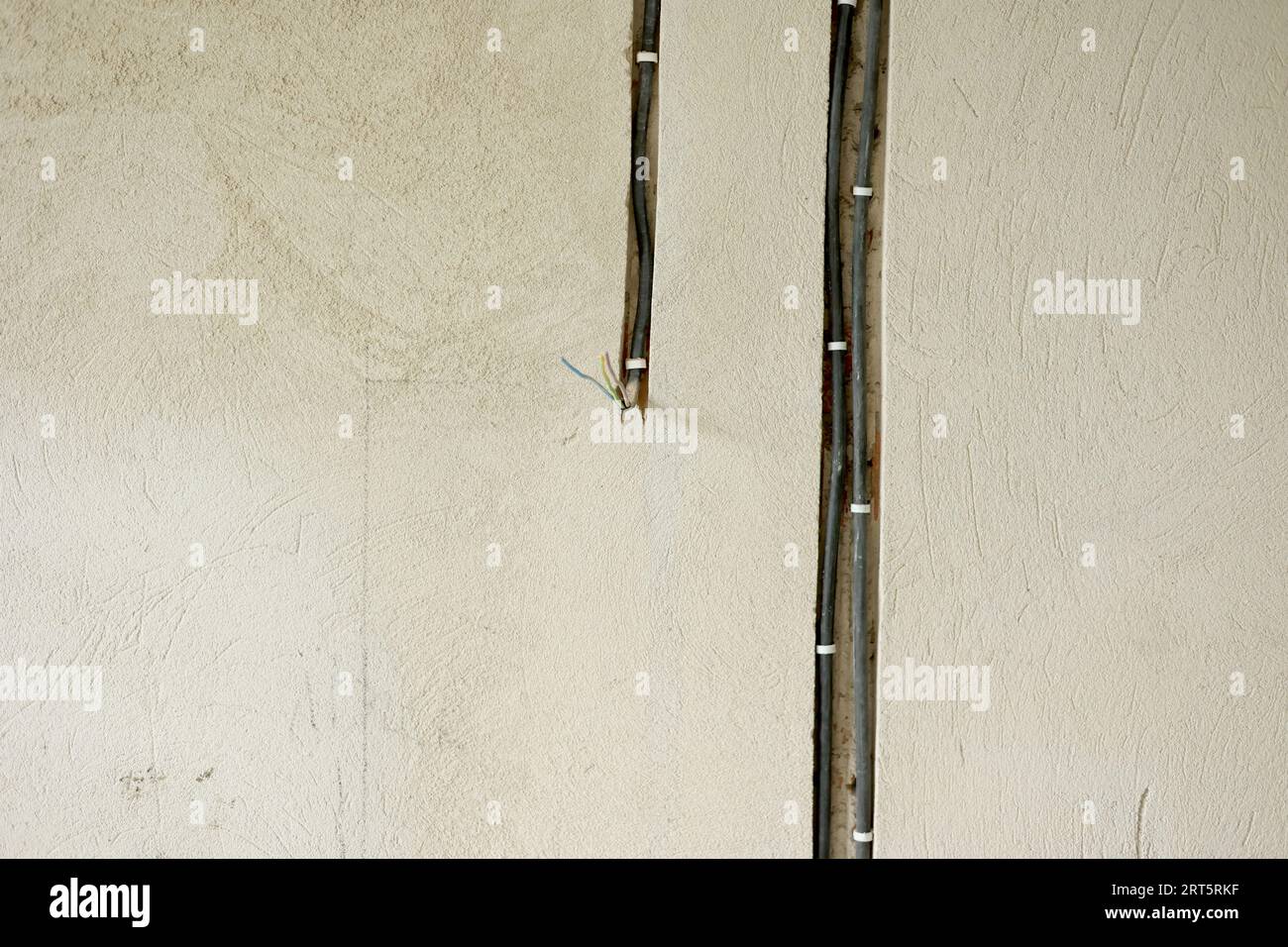 Wiring electrical cables on building concrete wall. Unfinished room ...