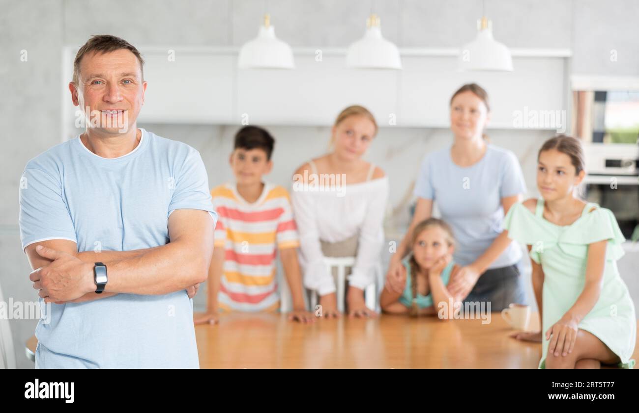Smiling dad poses in cozy kitchen, large family with four children and ...