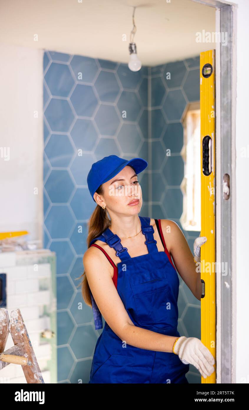 Woman builder in blue overalls measures deviations from a given ...