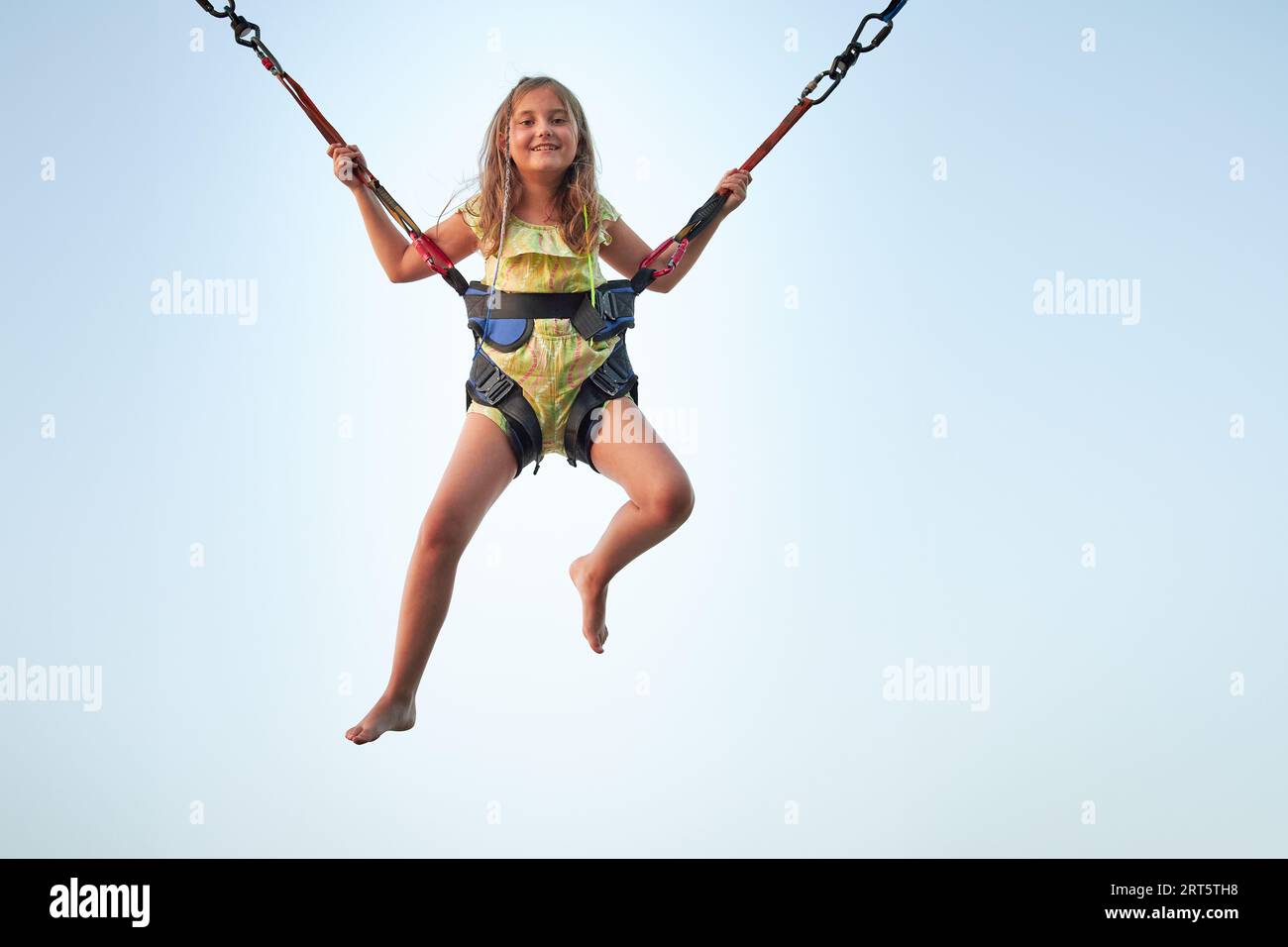 Bungee jumping at trampoline. Little girl bouncing on bungee jumping in ...