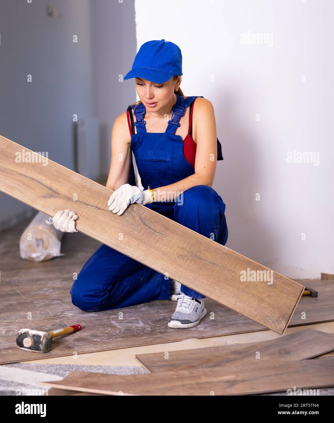Female worker in blue construction overalls and cap installing new ...