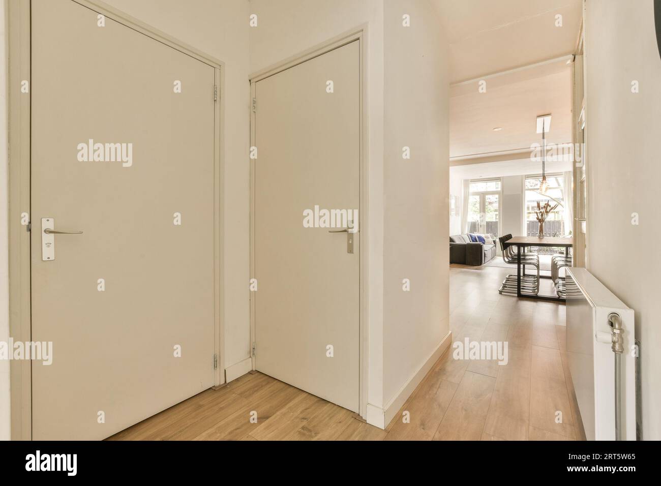 a hallway with white walls and wood flooring on the right side, there ...