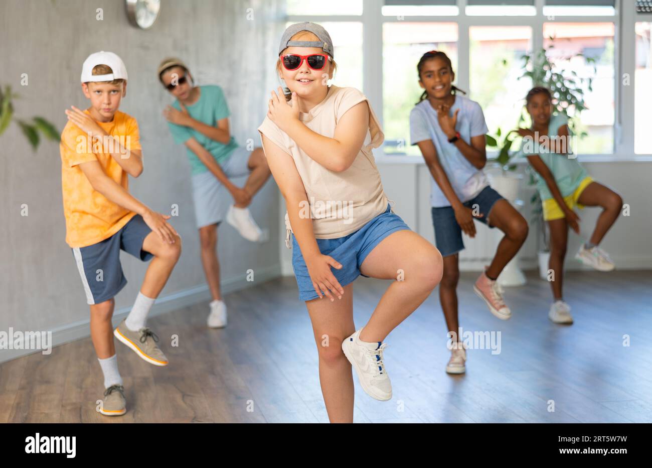 Smiling tween girl dancing krump with group of children in dance studio ...
