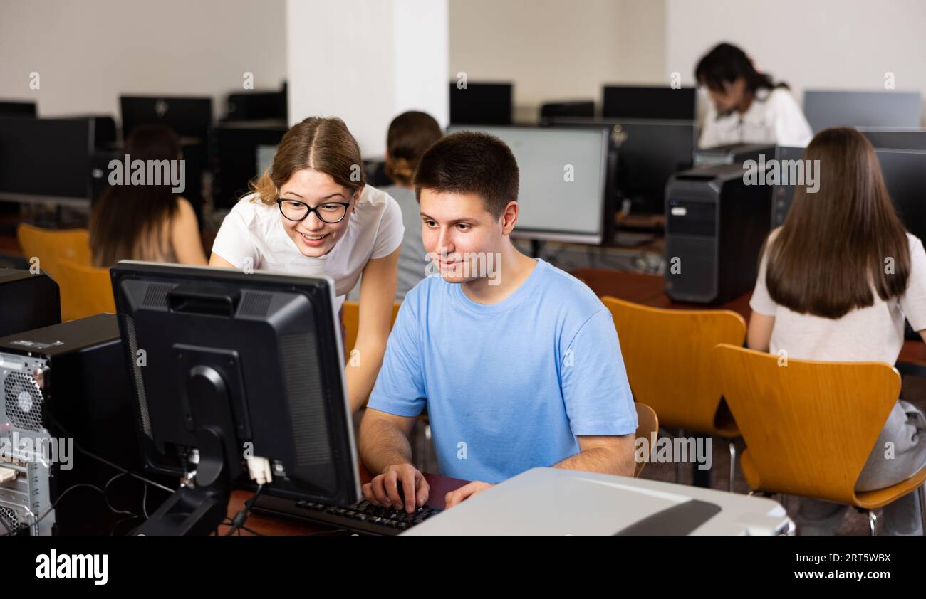 Cheerful teenager boy and girl studying in computer class Stock Photo ...