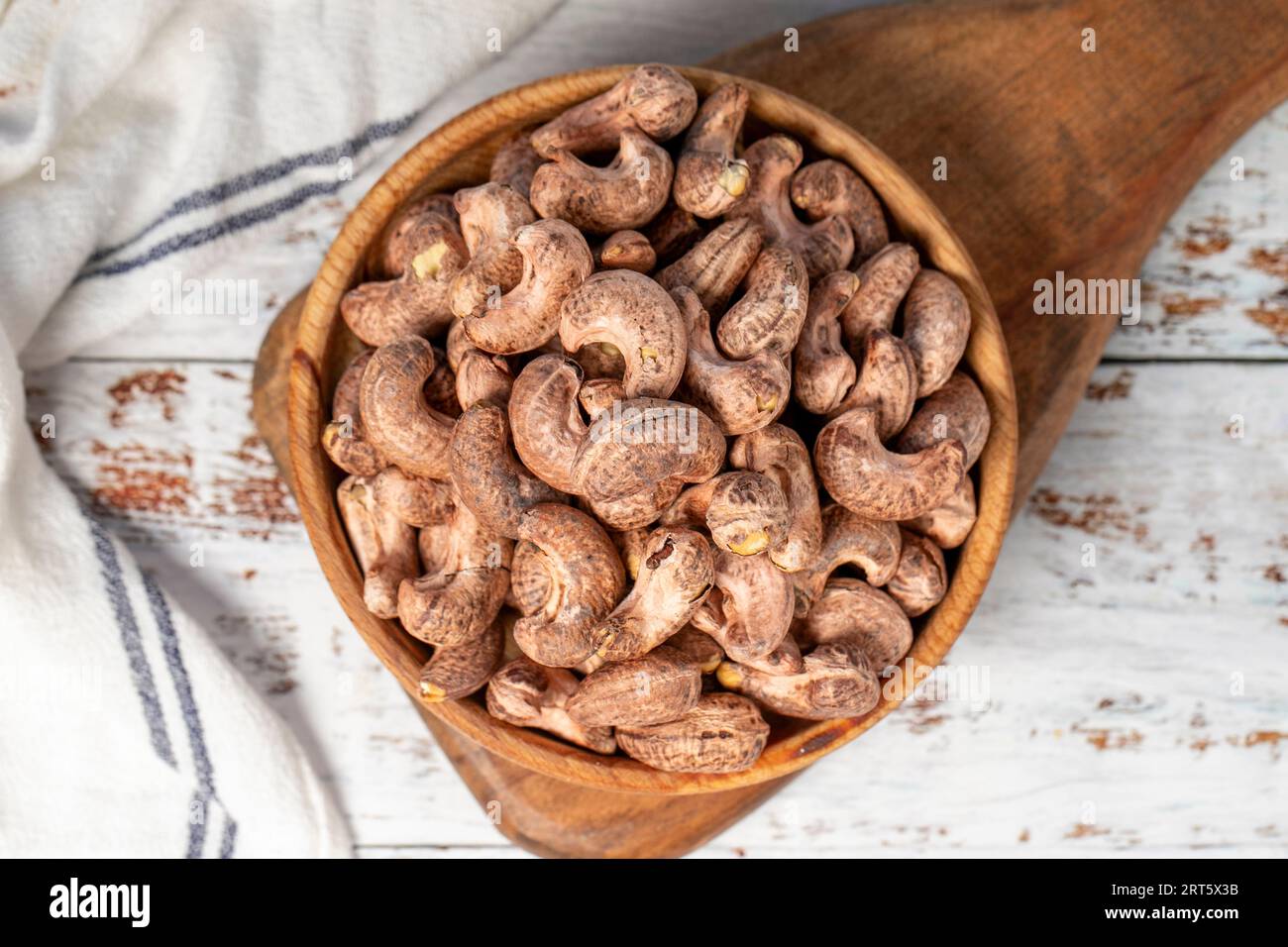 Cashews with shell in wood bowl. Shelled cashew on white wood ...