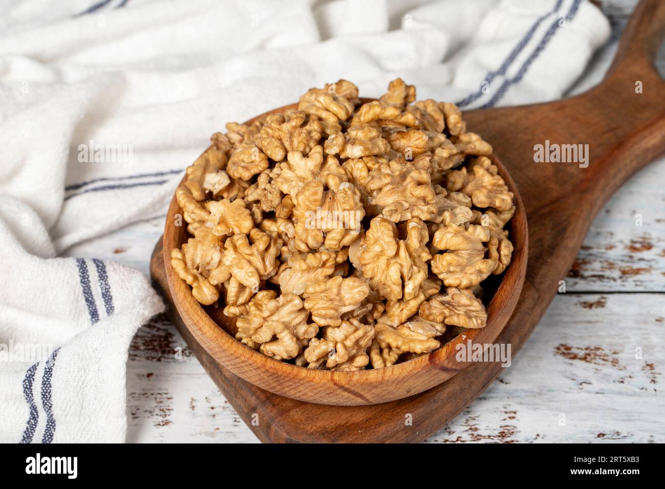 Walnut in wood bowl. Walnut peeled on white wood background Stock Photo ...
