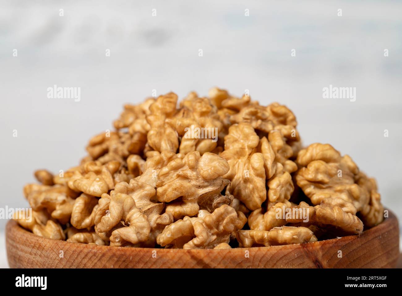 Walnut in wood bowl. Walnut peeled on white wood background. Close up ...