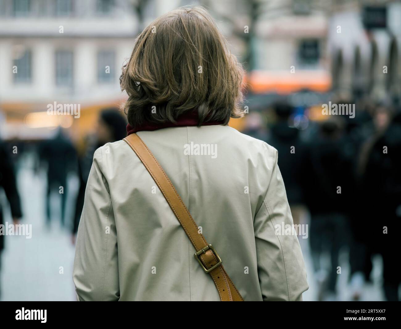 An unidentifiable woman is captured from the rear, donned in a trench ...