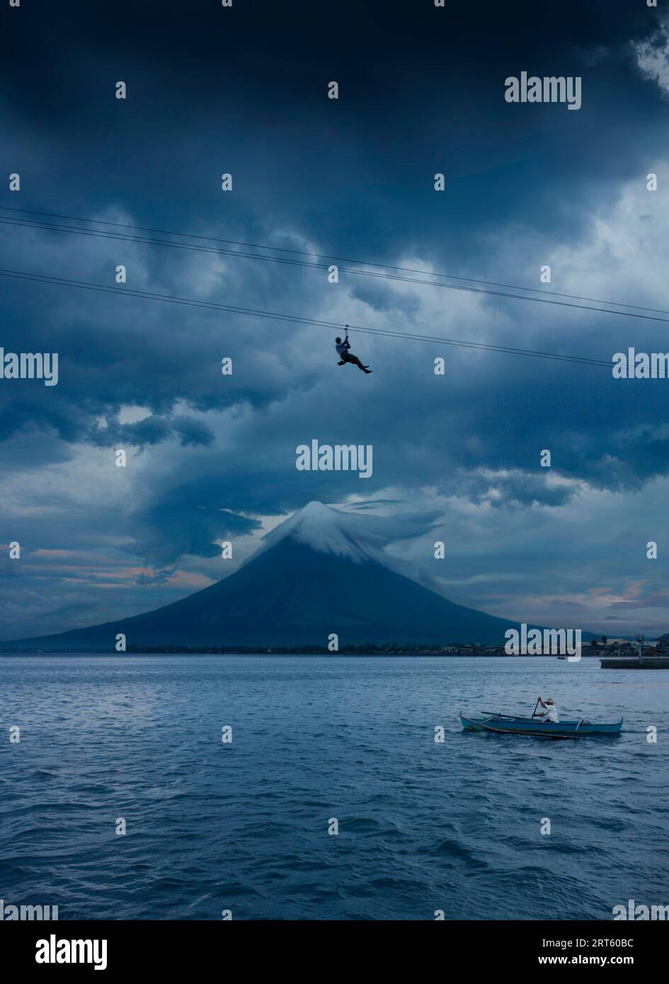 Man on zipline over bay of Legazpi City with Mayon Volcano Stock Photo ...