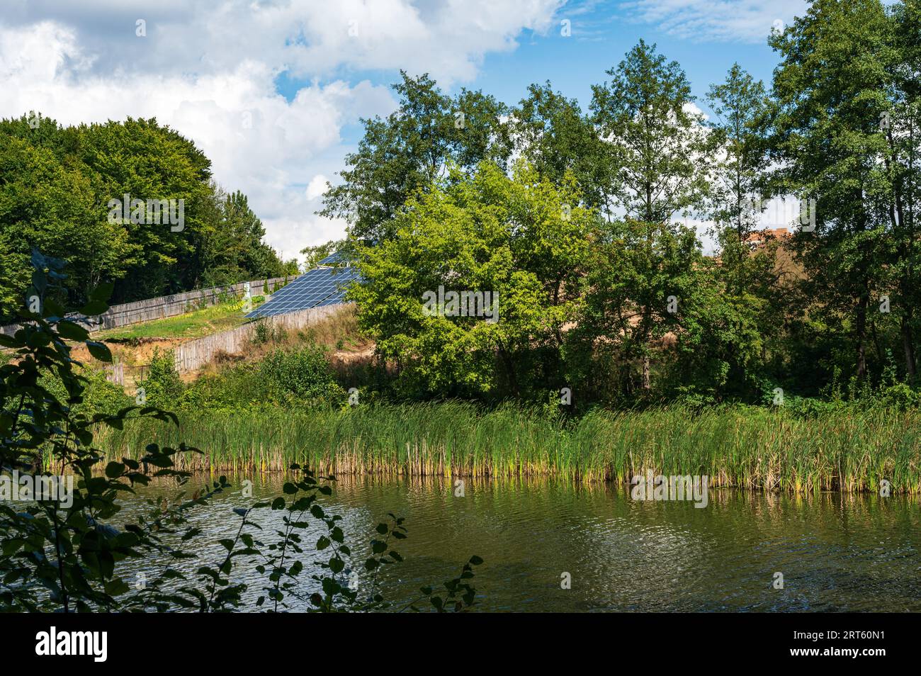 Small solar power station with solar panels near water on bank of river ...