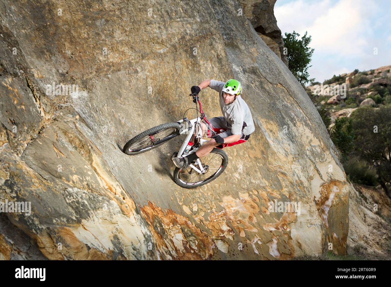 Mountain bike athlete does a wall ride on a trail in the mountains of ...