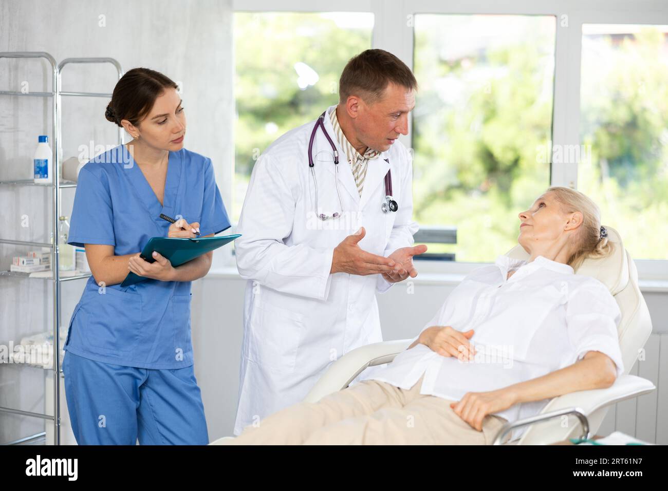 Female nurse and male doctor carries out survey of mature female ...