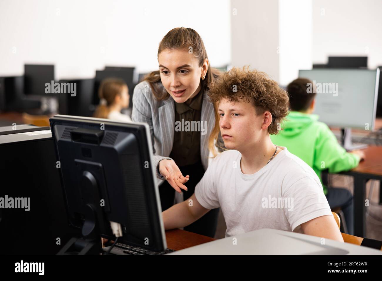 Teacher explaining task solution to pupil during computer science ...