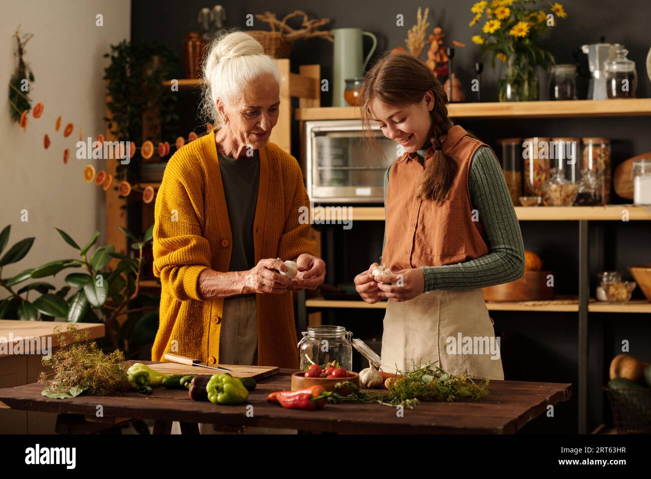 Senior woman explaining her granddaughter how to peel garlic for ...