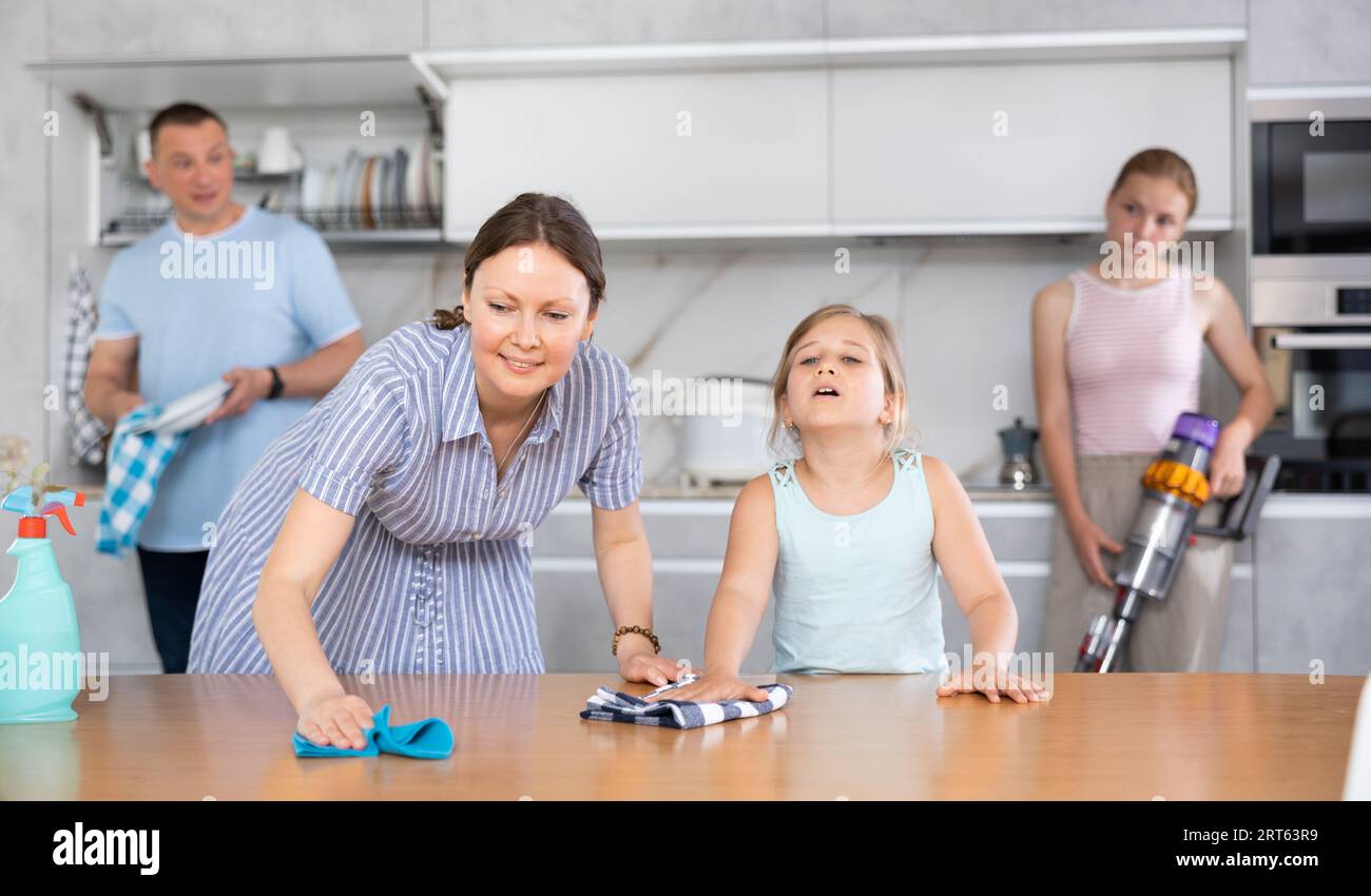 Friendly family tidy up room together. Mom and daughter are dusting the ...