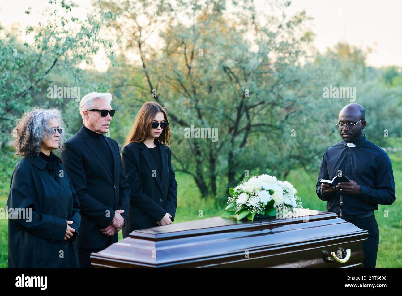 African American pastor with open Bible and mourning family in black ...