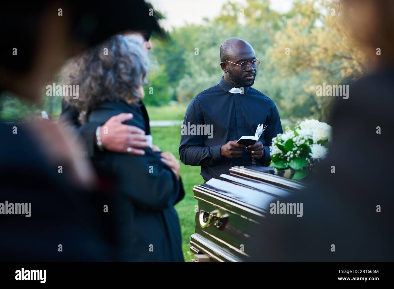 Focus on young pastor with Holy Bible and rosary beads standing in ...
