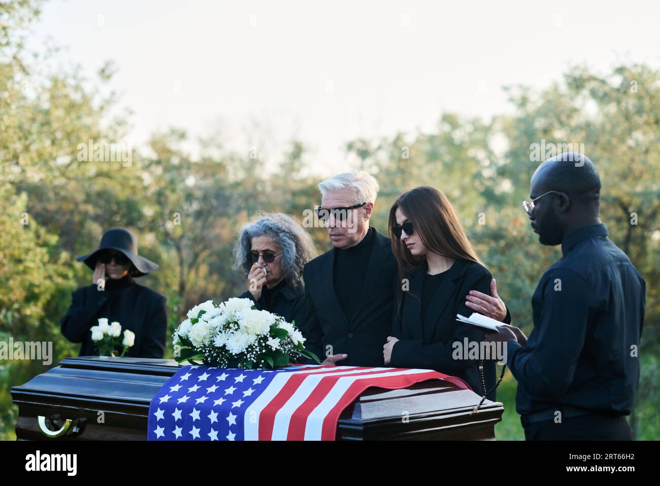 Pastor with Holy Bible and mourning family of three standing in front ...