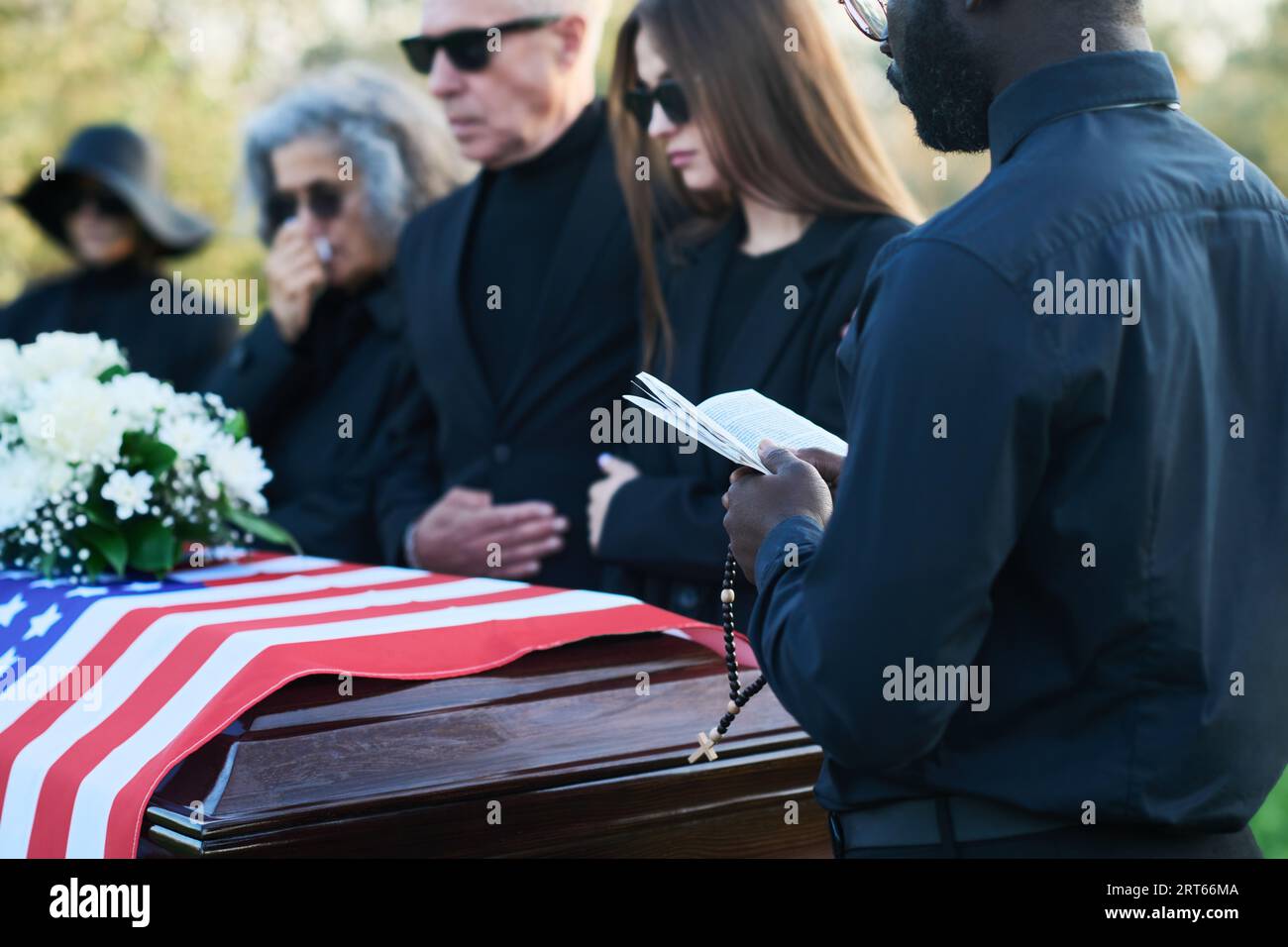 Cropped shot of African American priest with open Bible carrying out ...