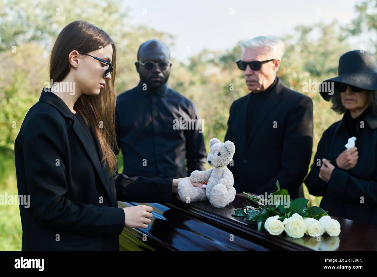 Young grieving woman in mourning attire and sunglasses putting grey ...