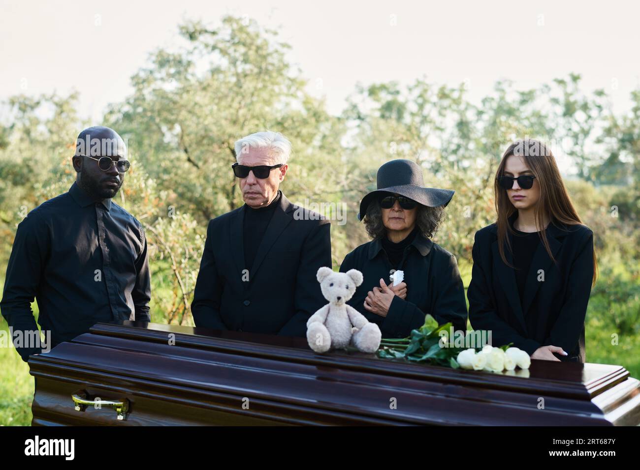 Group of grieving intercultural people in mourning clothes gathered by ...