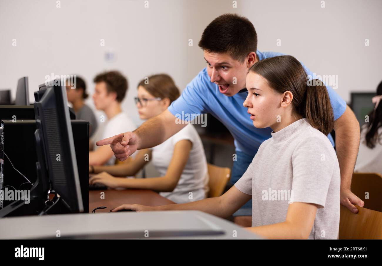 Clever male teenager helping to the female classmate while she is ...