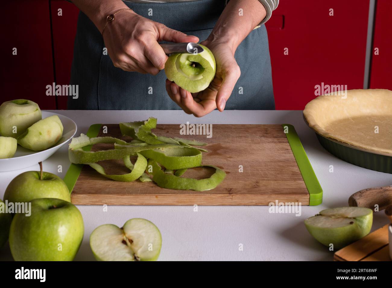 Woman is peeling apples to prepare apple pie in the kitchen. Authentic ...