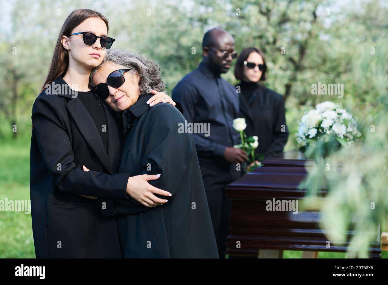 Mature grieving woman in sunglasses and mourning attire keeping head on ...