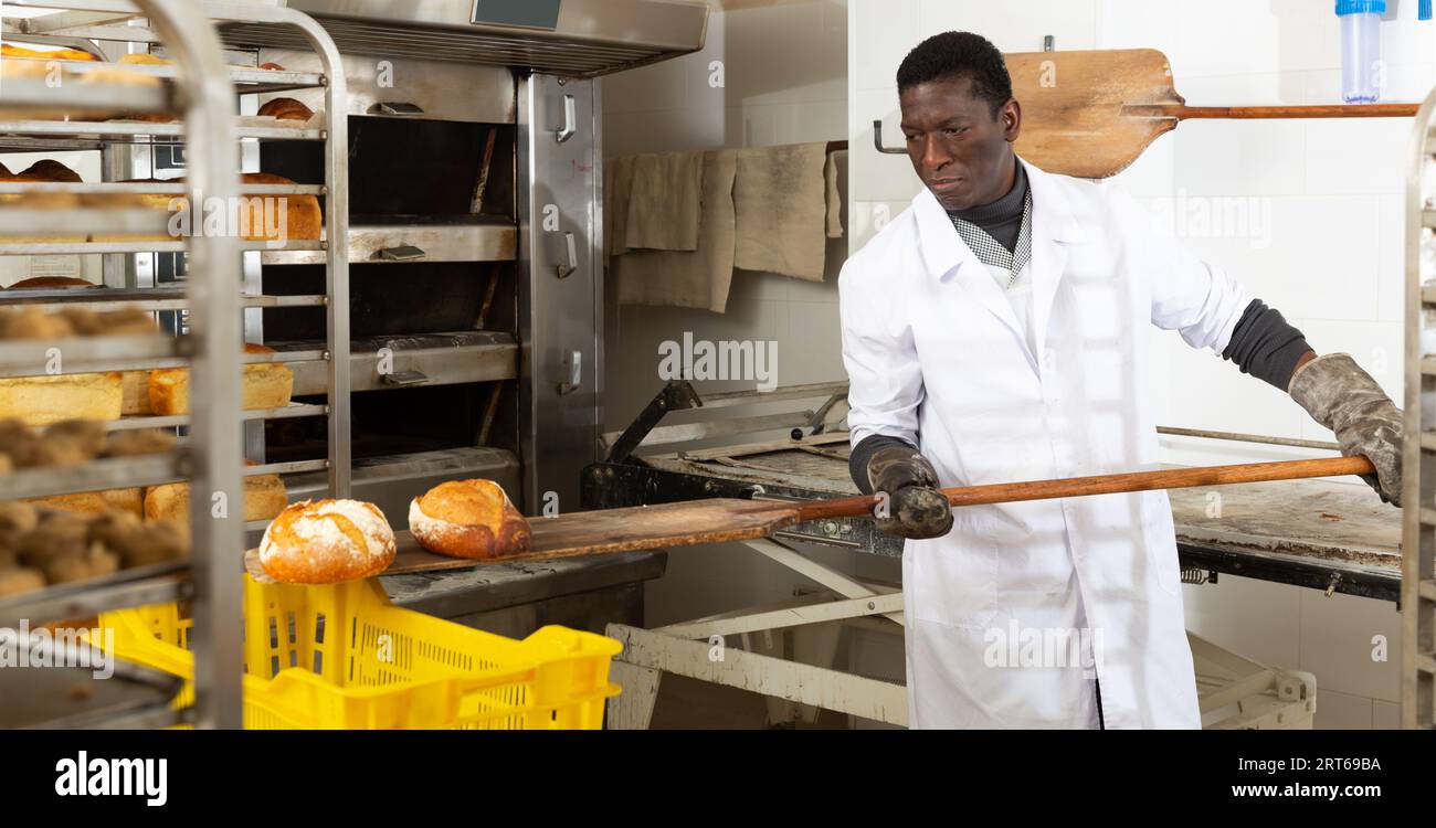 African baker pulling loaves from oven Stock Photo - Alamy