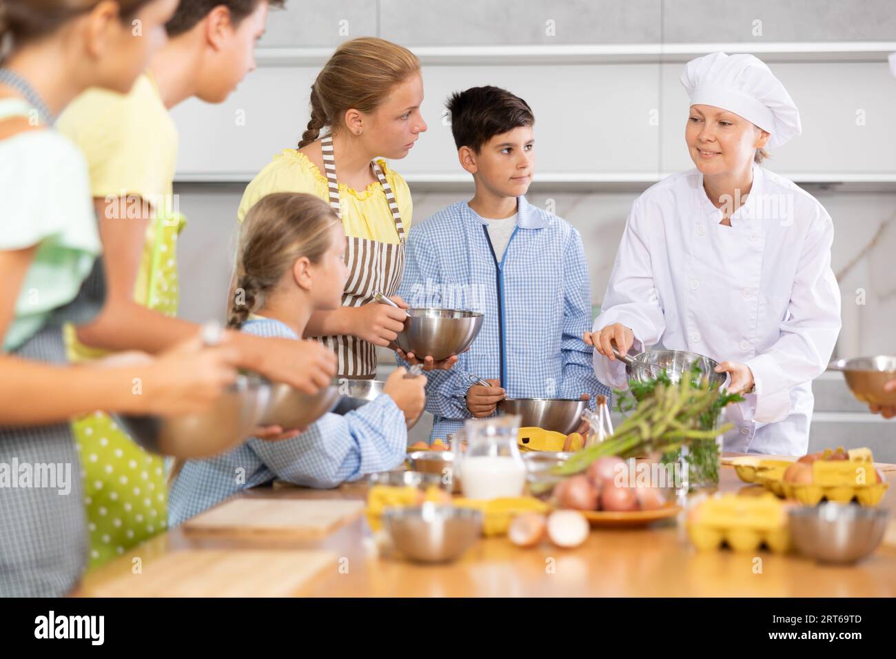 Amiable female chef running culinary courses for preteen children Stock ...