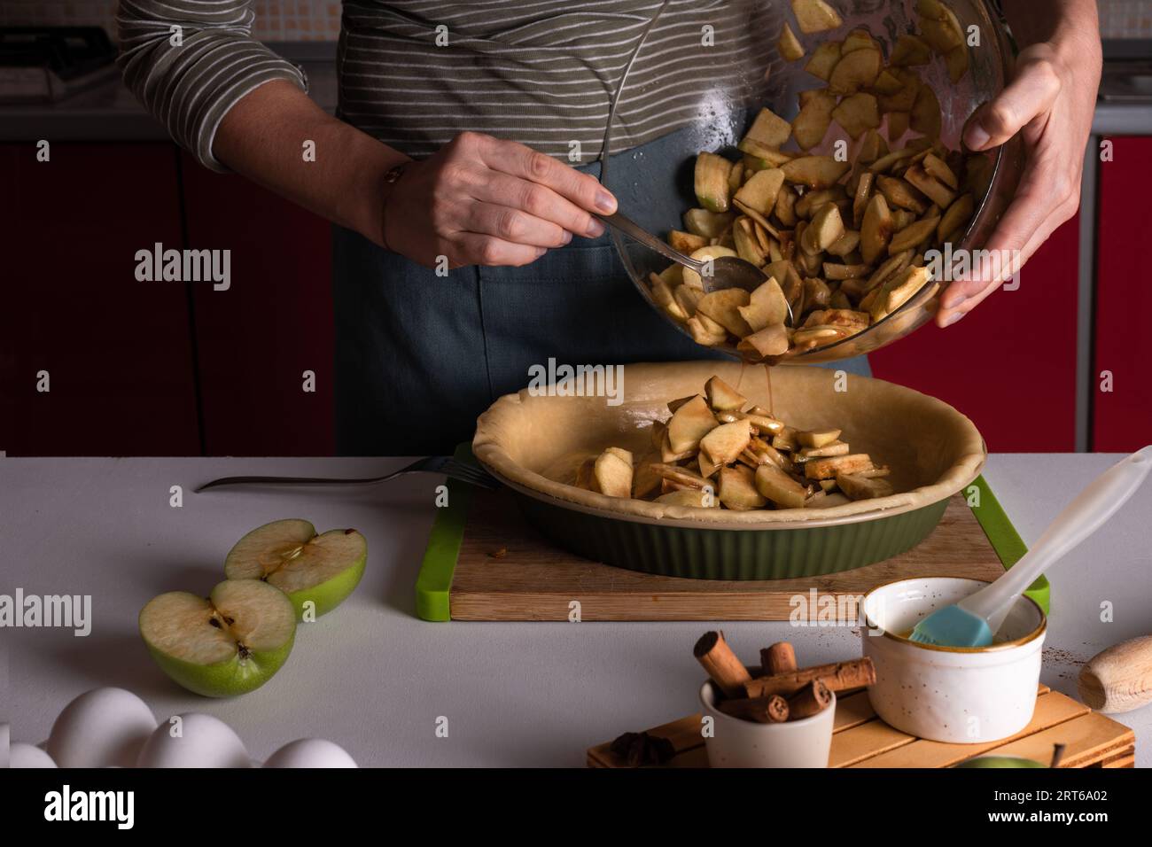 woman pouring spiced apples stuffing for the apple pie in the bakery ...
