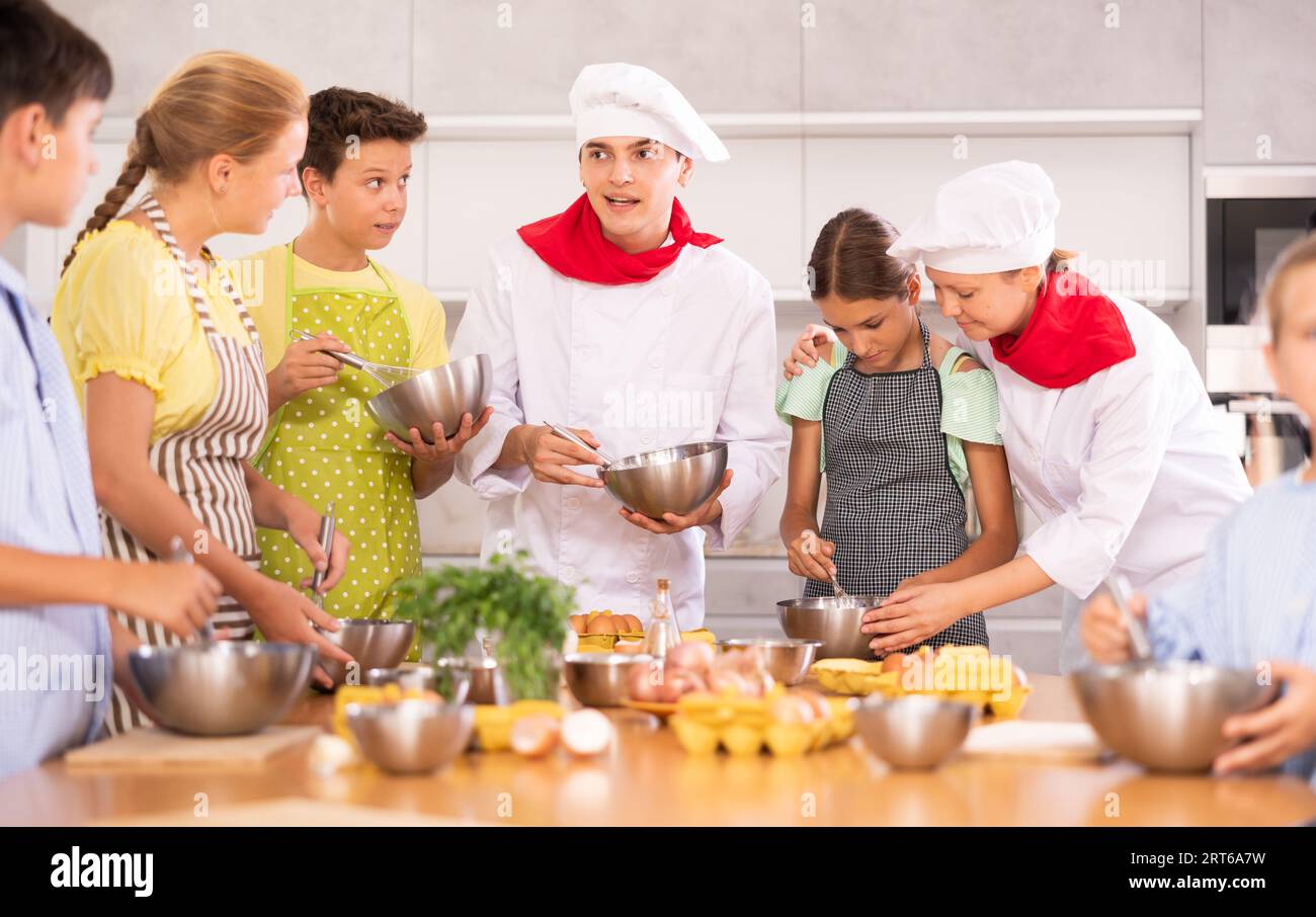 Young chef giving culinary classes to group of interested tweens Stock ...