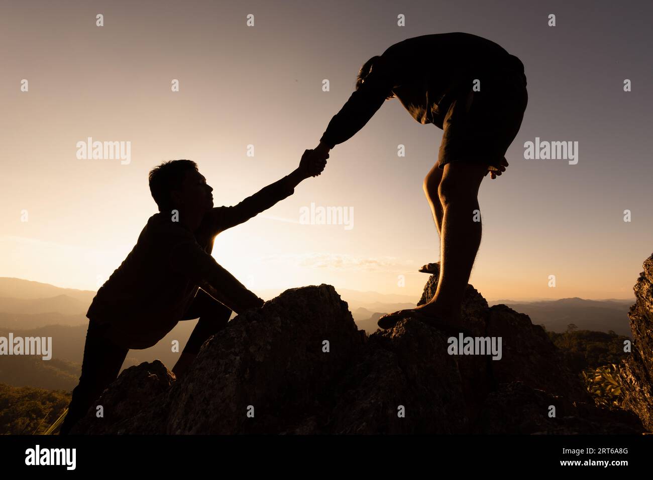 Silhouettes of two people climbing on mountain and helping. Help and ...