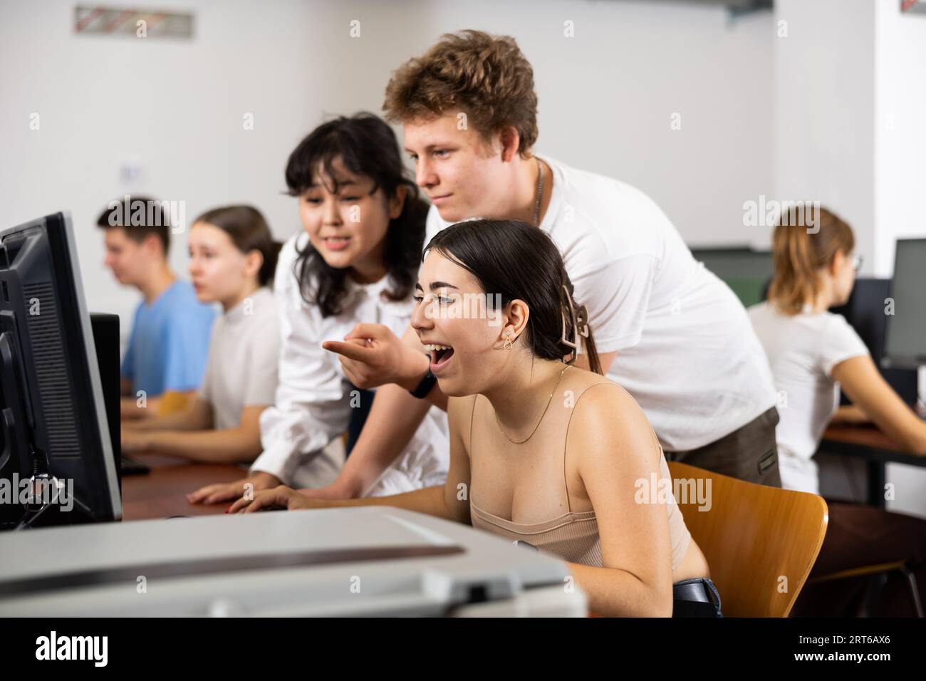 Surprised teenagers looking at the screen of PC while learning the computer science in the ...