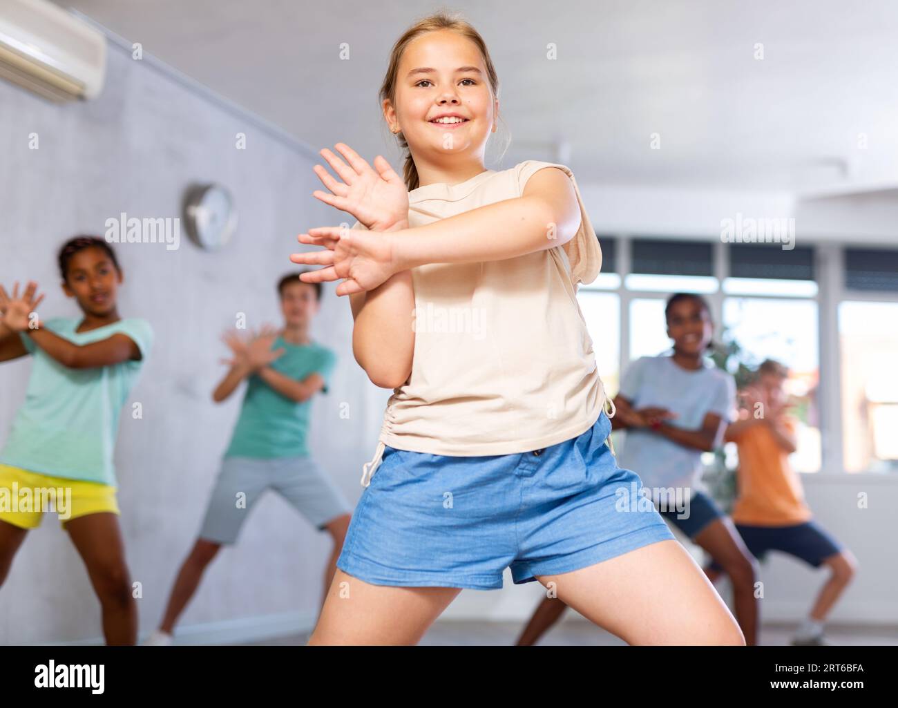 Positive juvenile girl engaged in Hip-hop dance in training room with ...
