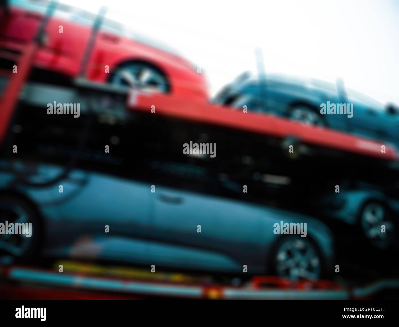 From a low vantage point, cars on a trailer appear in a defocused ...