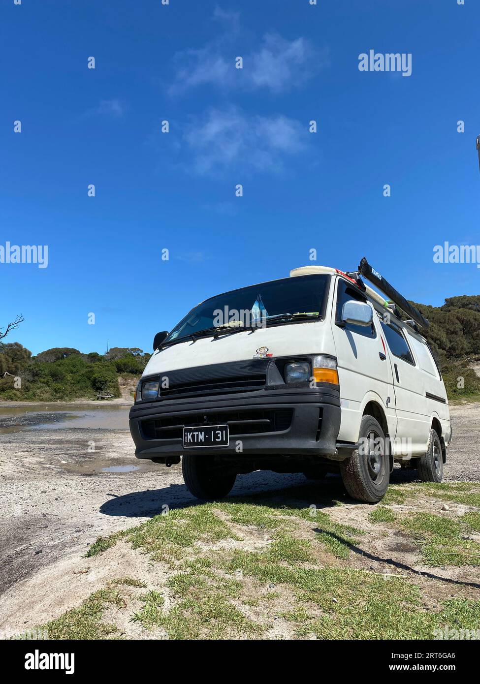 A vertical shot of a white Toyota Hiace Van off-road on sand dune on a ...