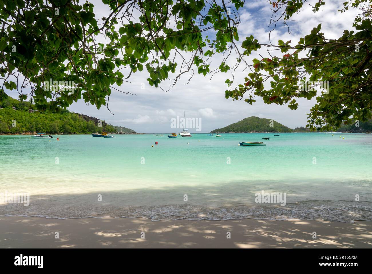 Colorful boats and transparent water in the lagoon of Port Launay beach ...