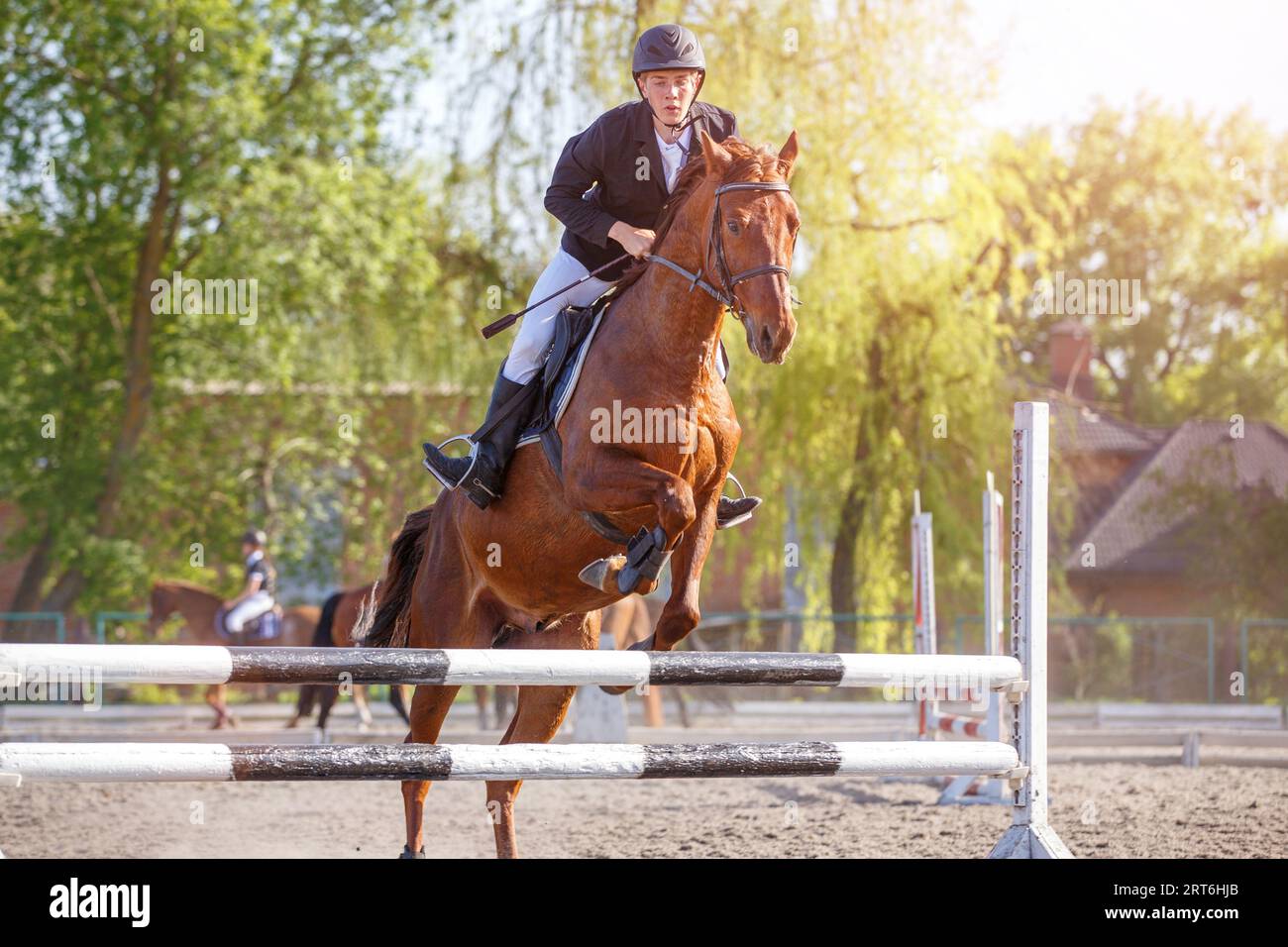 Young sportsman riding horse bounding over obstacle on showjumping ...