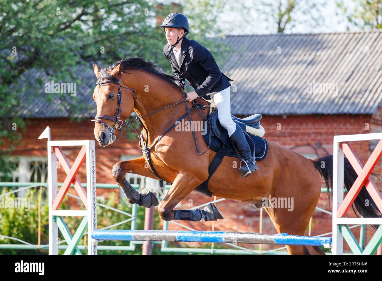 Young sportsman riding horse bounding over obstacle on showjumping ...