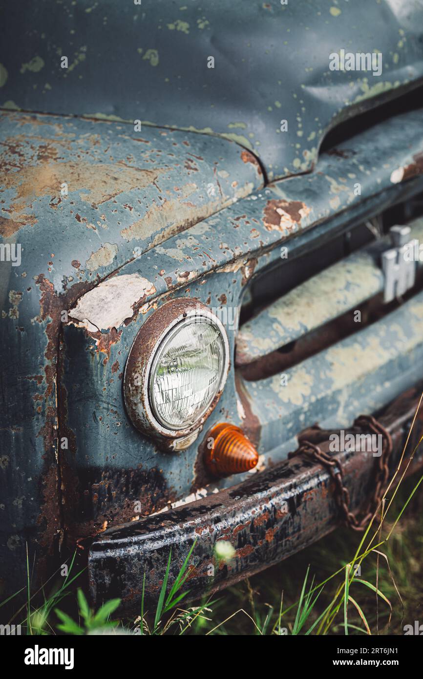 A vintage blue pickup truck parked in a grassy field with a distressed ...