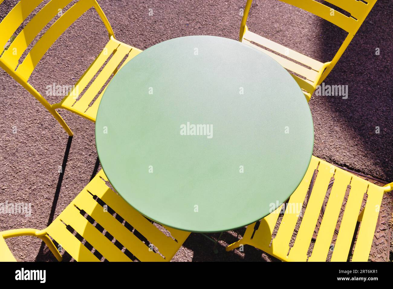 picture of a green bistro table with yellow chairs, seen from above ...