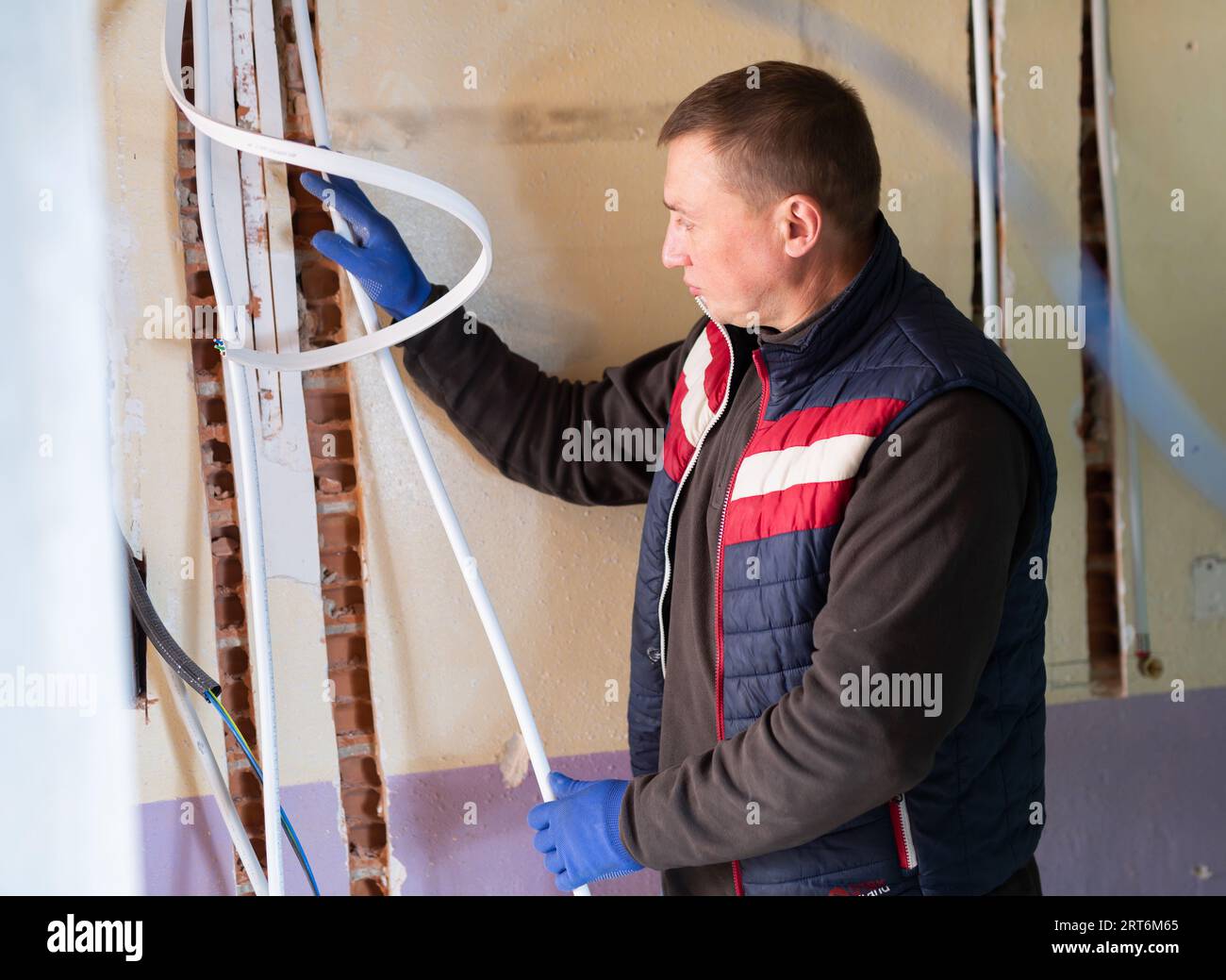 Plumber installs new plastic pipes in special boxes in the wall in ...