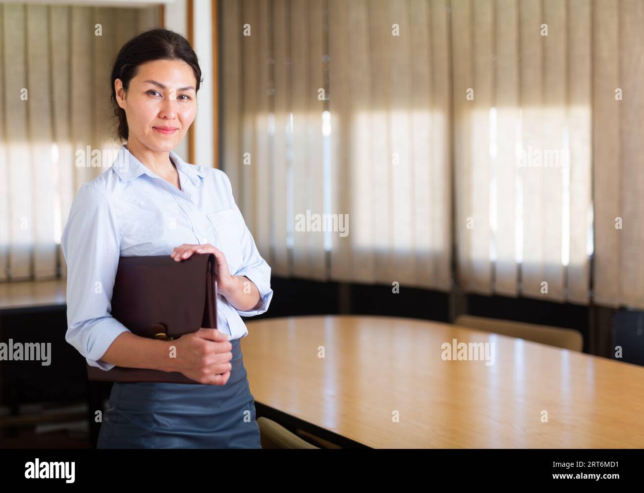 Successful businesswoman with briefcase standing near conference table ...